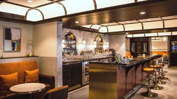 Uma área de bar com balcão, bancos e um espaço de estar com um sofá e cadeiras.