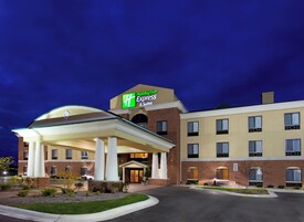 Um hotel Holiday Inn Express & Suites com entrada coberta, fachada de tijolos e várias janelas.