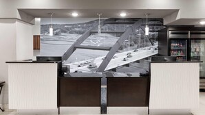 Uma área de recepção com um grande mural de uma ponte, um balcão e um refrigerador.