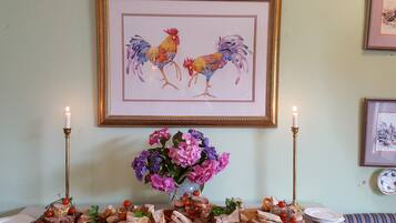 Uma mesa com sanduíches e tomates cereja, um vaso de flores e duas velas acesas.