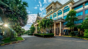 Um hotel grande com um pátio central, palmeiras e uma estátua de um elefante.