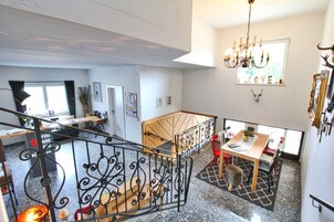 Um interior amplo com escada, área de jantar e lustre.