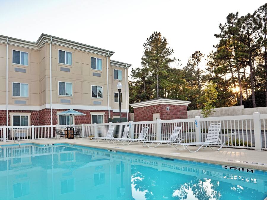 Hotel com piscina, área de estar externa e edifício de tijolos.
