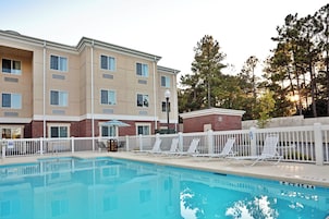 Hotel com piscina, área de estar externa e edifício de tijolos.