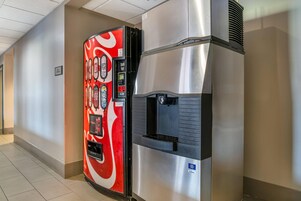 Máquina de vendas automática com logomarca Coca-Cola, dispensador de bebidas e um aviso que diz 'Obrigado!'.