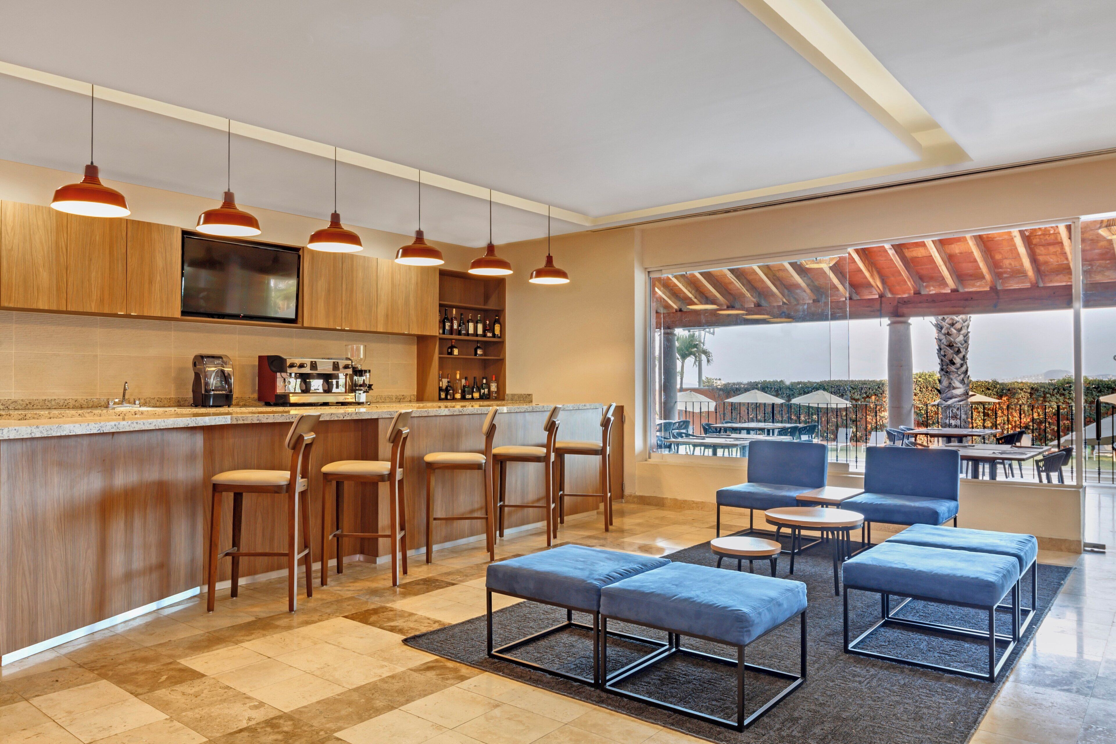 Cozinha moderna com área de bar, assentos com pufes e vista para o exterior.