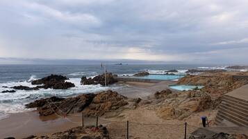 Uma praia rochosa com piscina e uma torre de salva-vidas.