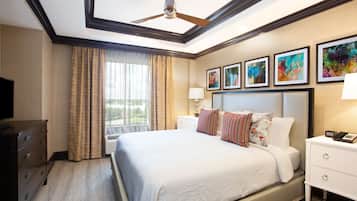 Quarto de hotel com uma cama grande, um ventilador de teto, mesa de cabeceira com telefone e janela com cortinas.