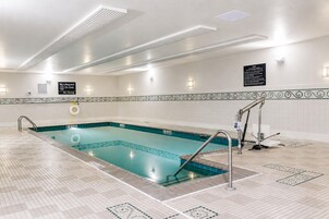 Piscina com deck revestido, cadeira de salva-vidas e placa de proibição de mergulho.