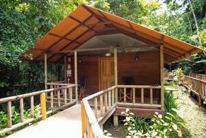 Uma cabana de madeira com varanda, deck de madeira e um pequeno jardim.