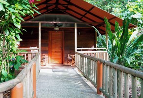 Uma cabana de madeira com varanda, ventilador de teto e porta com placa de número.