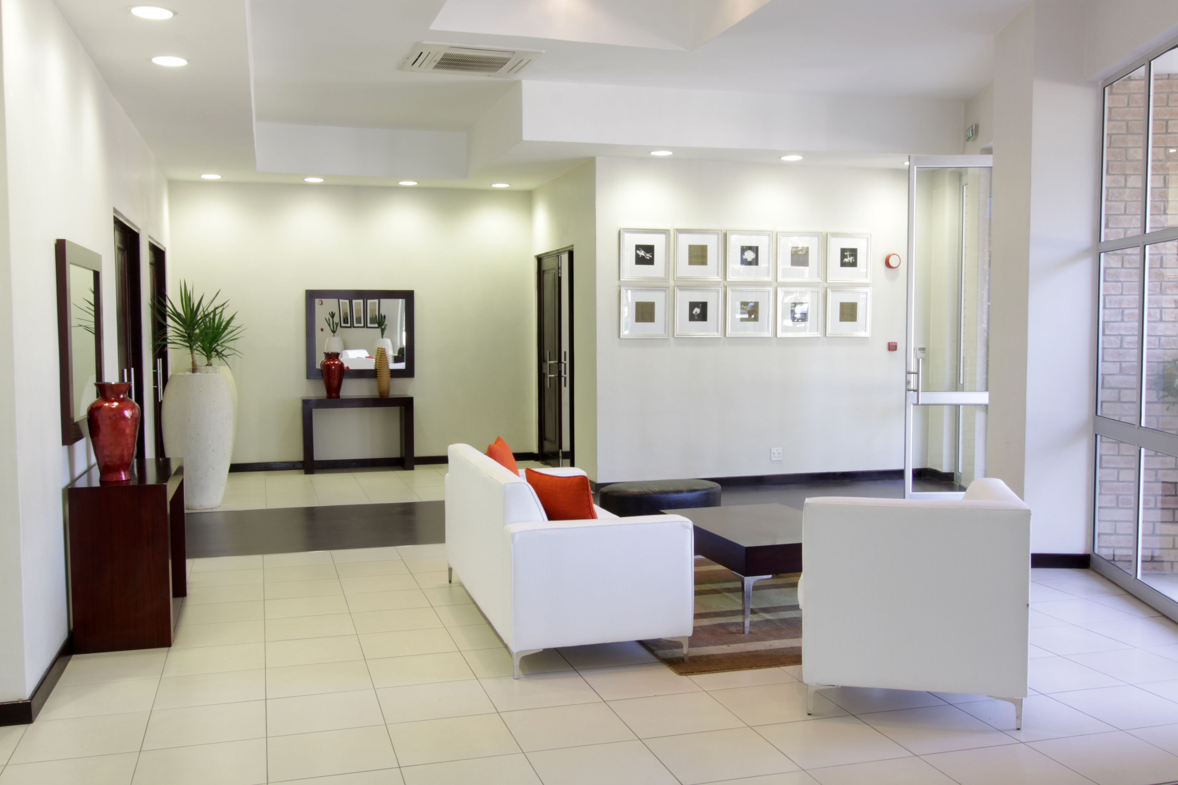 Um lobby moderno com sofás brancos, uma mesa de centro e um balcão de recepção.