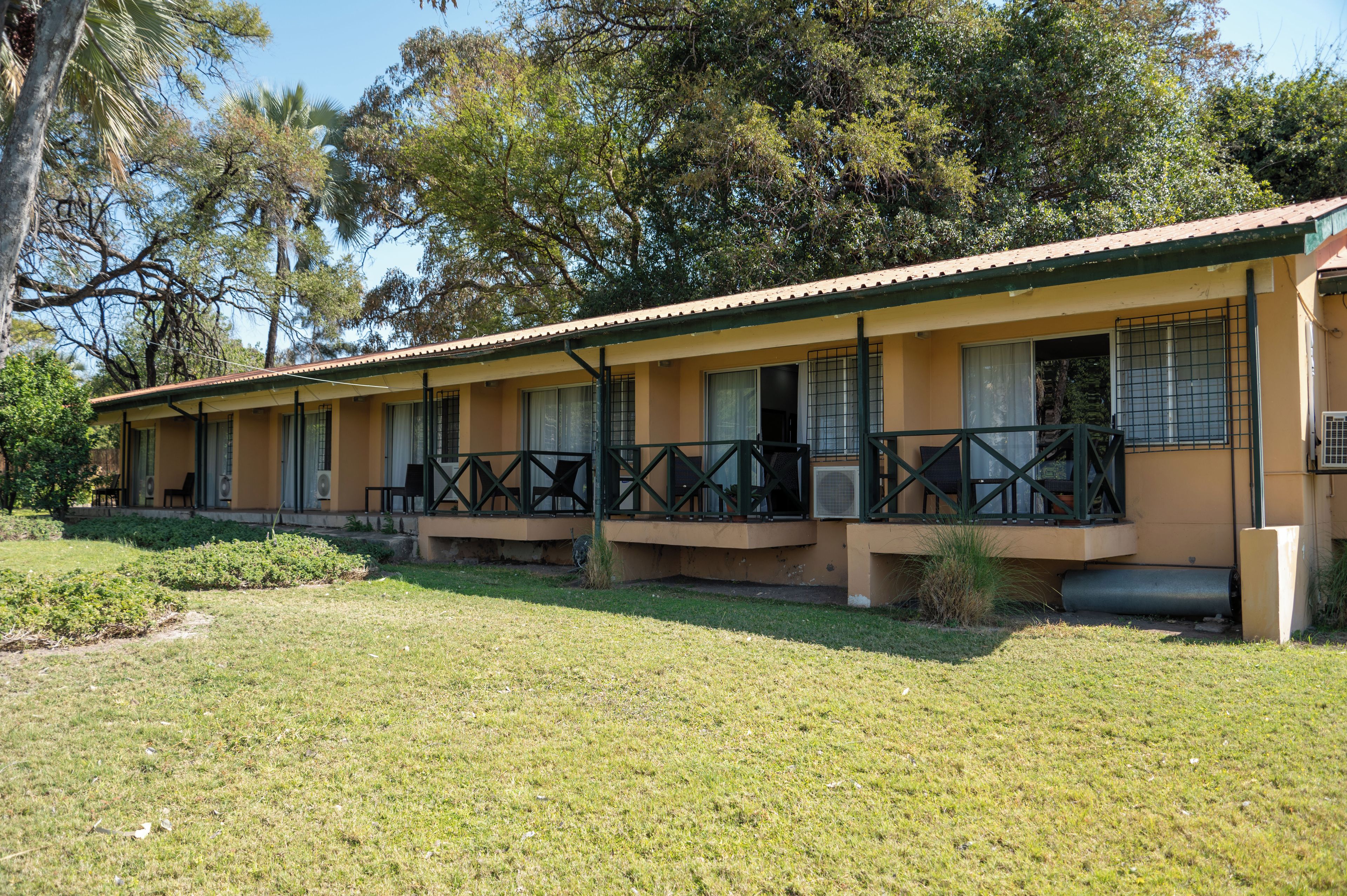 Um motel de dois andares com telhado plano, várias janelas e uma área de estar coberta ao ar livre.
