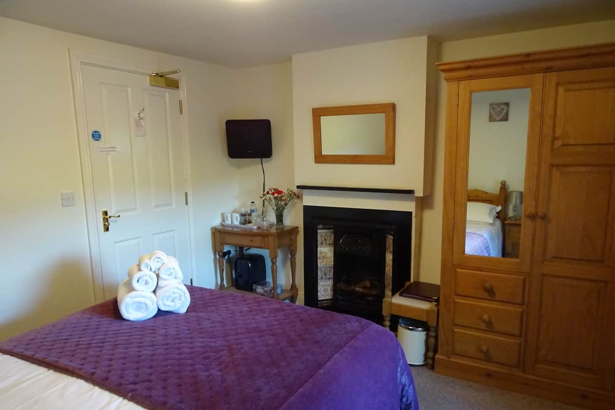 Quarto com uma cama, penteadeira de madeira, lareira e espelho.