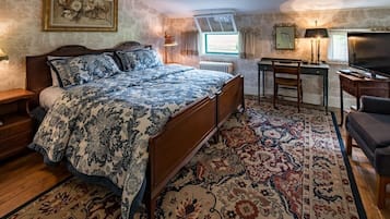 Quarto com cama de madeira, escrivaninha, cadeira, televisão e radiador.