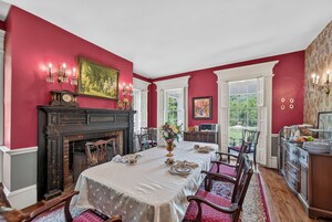 Uma sala de jantar com lareira, mesa posta para quatro pessoas e vista para o exterior através de grandes janelas.