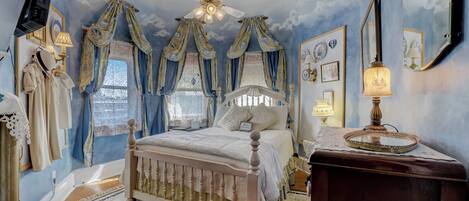 Quarto com cama, ventoinha no teto, mesa de cabeceira e cômoda.