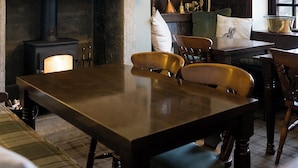Uma sala de estar acolhedora com lareira, uma mesa de jantar e um candelabro.