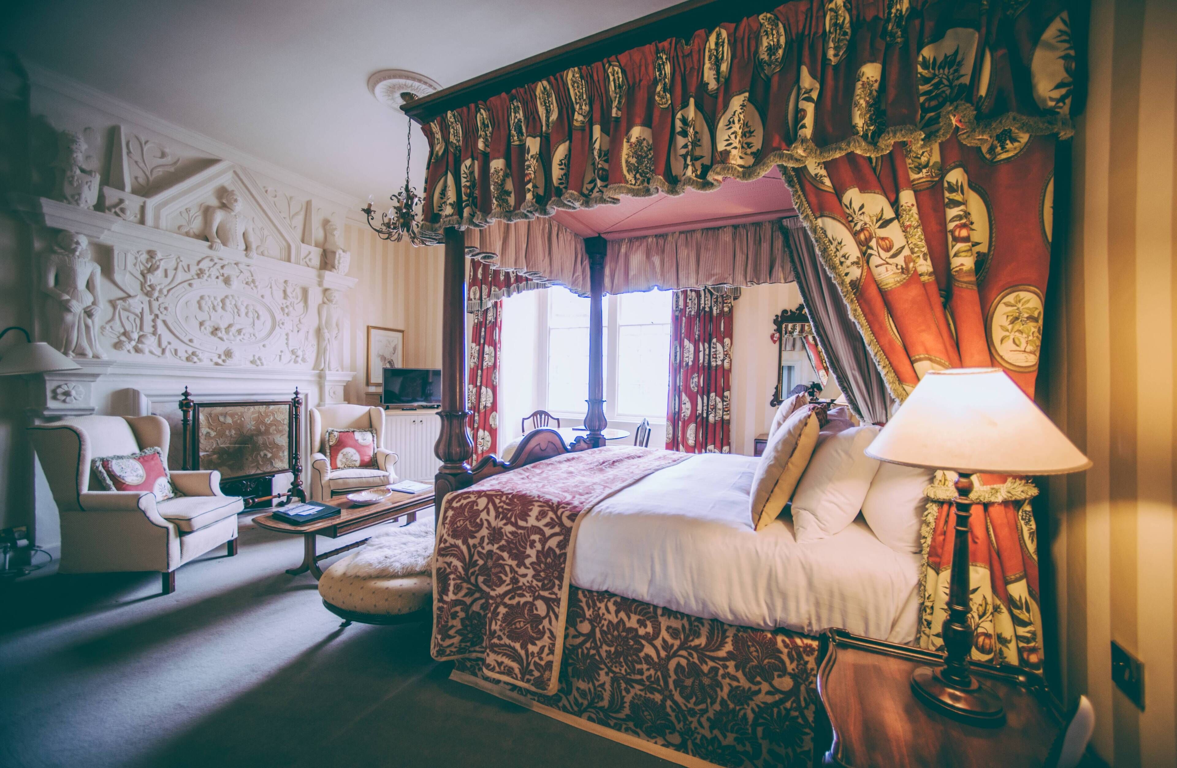 Um quarto tradicional com cama de dossel, lareira e decoração clássica.