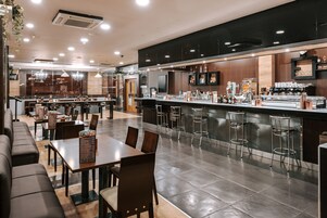 Restaurante moderno com área de bar, diferentes opções de assentos e um balcão com diversos itens.