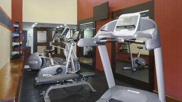 Academia com esteiras, elípticos e bolas de exercício.