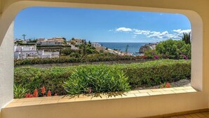 Uma varanda com vista para uma cidade costeira, com edifícios e céu claro.