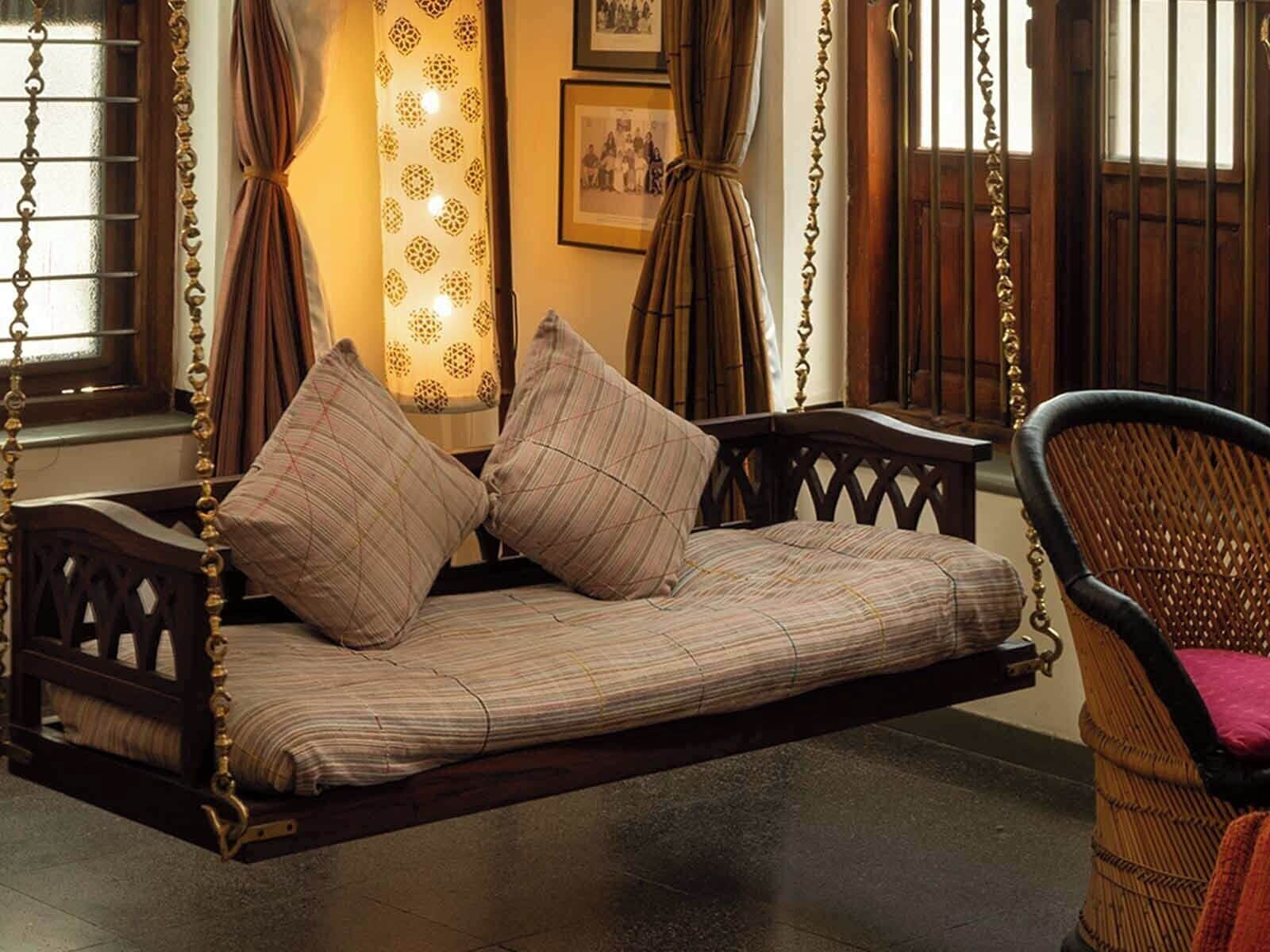 Quarto tradicional com uma rede de madeira, uma cadeira de vime e cortina estampada.
