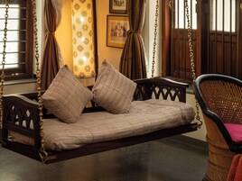 Quarto tradicional com uma rede de madeira, uma cadeira de vime e cortina estampada.