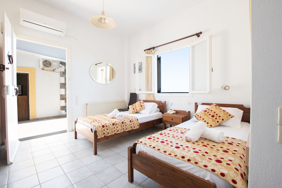 Quarto de hotel com duas camas, um espelho grande e um aparelho de ar condicionado.