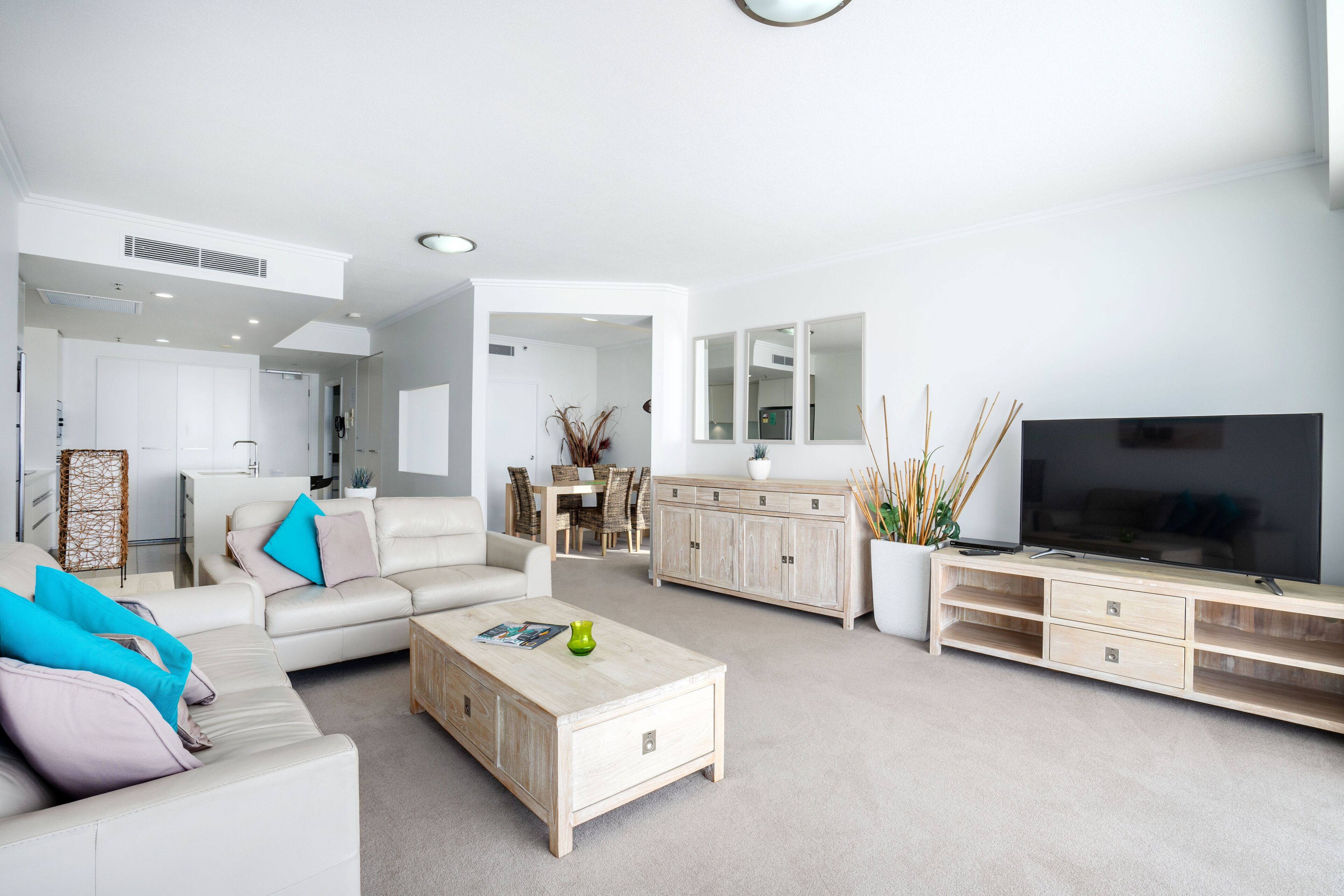 Uma sala de estar moderna com sofá, mesa de centro, rack para TV e área de refeições.