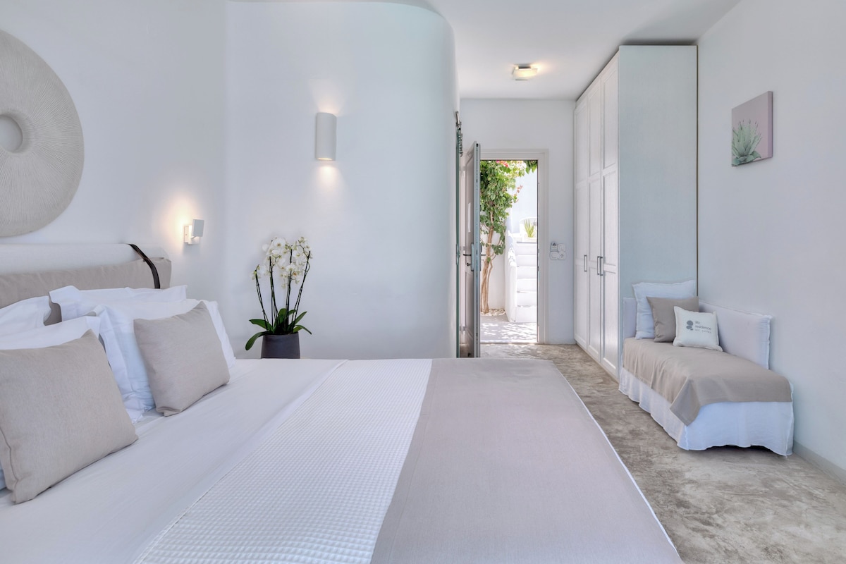 Quarto moderno com uma cama grande, uma mesa de cabeceira com uma planta e um guarda-roupa.