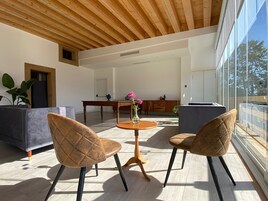 Uma sala de estar moderna com teto de madeira, área de jantar e amplas janelas.