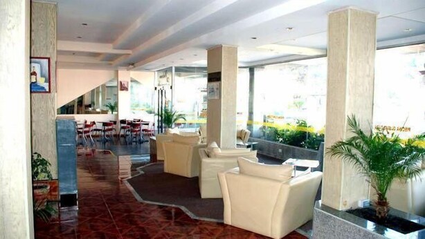 Um saguão de hotel com área de recepção, sofás e grandes janelas.