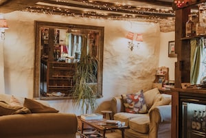 Uma sala de estar aconchegante com um espelho grande, uma planta e uma mesa de centro com livros.
