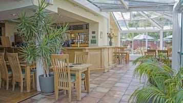 Um restaurante com mobiliário de madeira, espaço de bar e plantas em vasos.
