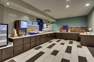 Uma cozinha moderna com barra de café da manhã, espaço para café e vitrine de confeitaria.