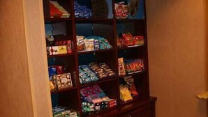 Um armário de madeira com várias prateleiras contendo diversos produtos alimentícios embalados.
