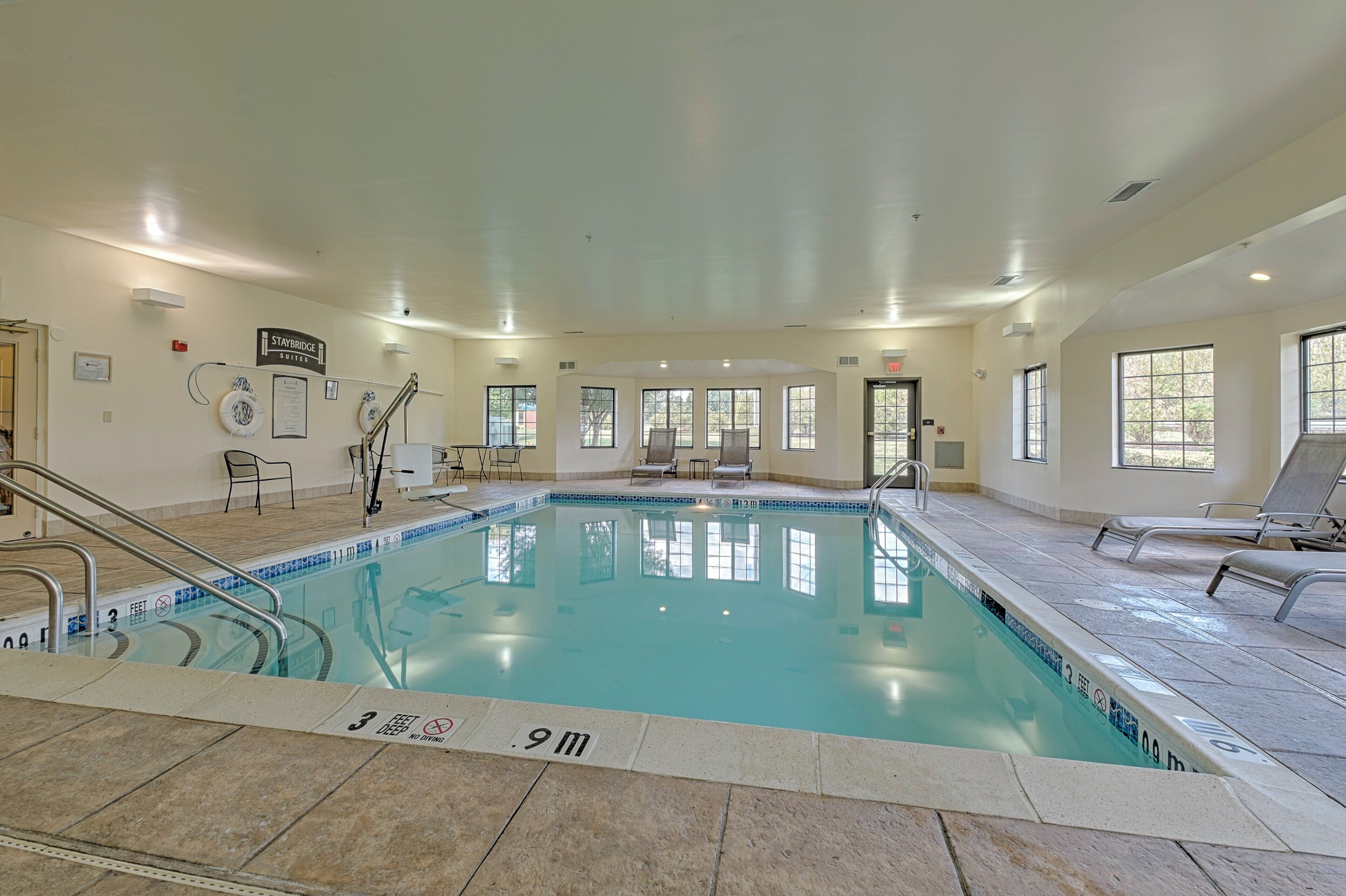 Piscina interna com água cristalina, indicadores de profundidade marcados e piso revestido com azulejos.