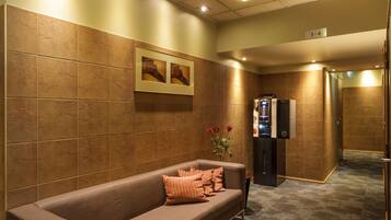 Um lobby moderno com um sofá de couro marrom, um vaso com flores e um balcão de recepção.