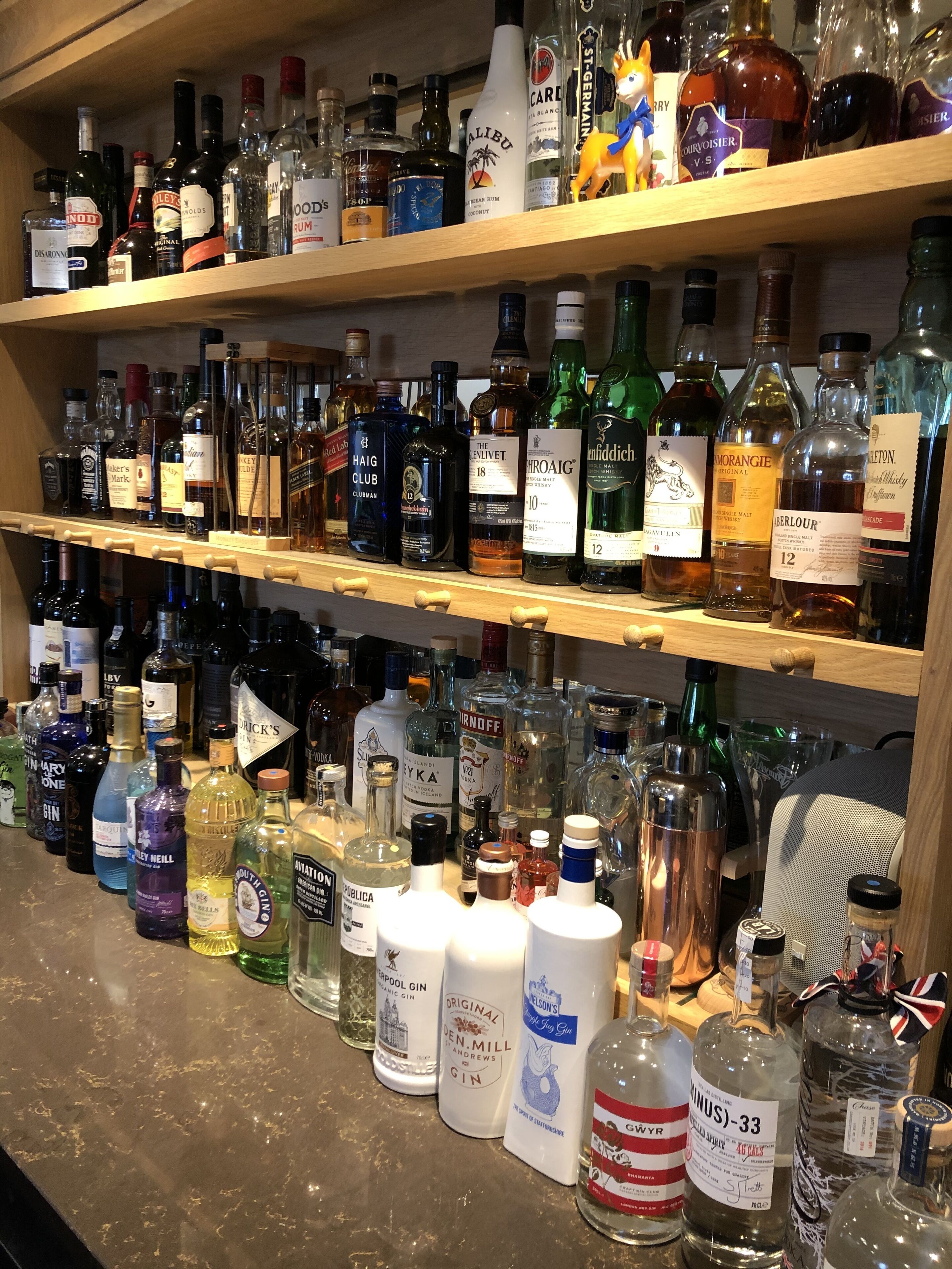 Uma área de bar com prateleiras repletas de diversas garrafas de bebidas alcoólicas.