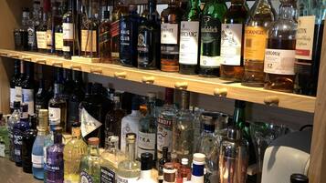 Uma área de bar com prateleiras repletas de diversas garrafas de bebidas alcoólicas.