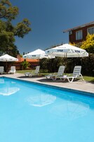 Área de piscina com espreguiçadeiras e guarda-sóis com a inscrição 'VISA'.