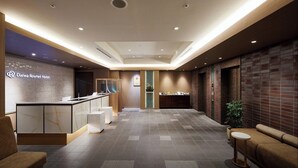 Um hall de hotel moderno com balcão de recepção, área de estar e televisão na parede.