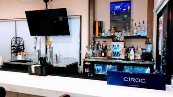 Uma área de bar com televisão de tela plana, torneira de cerveja e diversos tipos de bebidas.