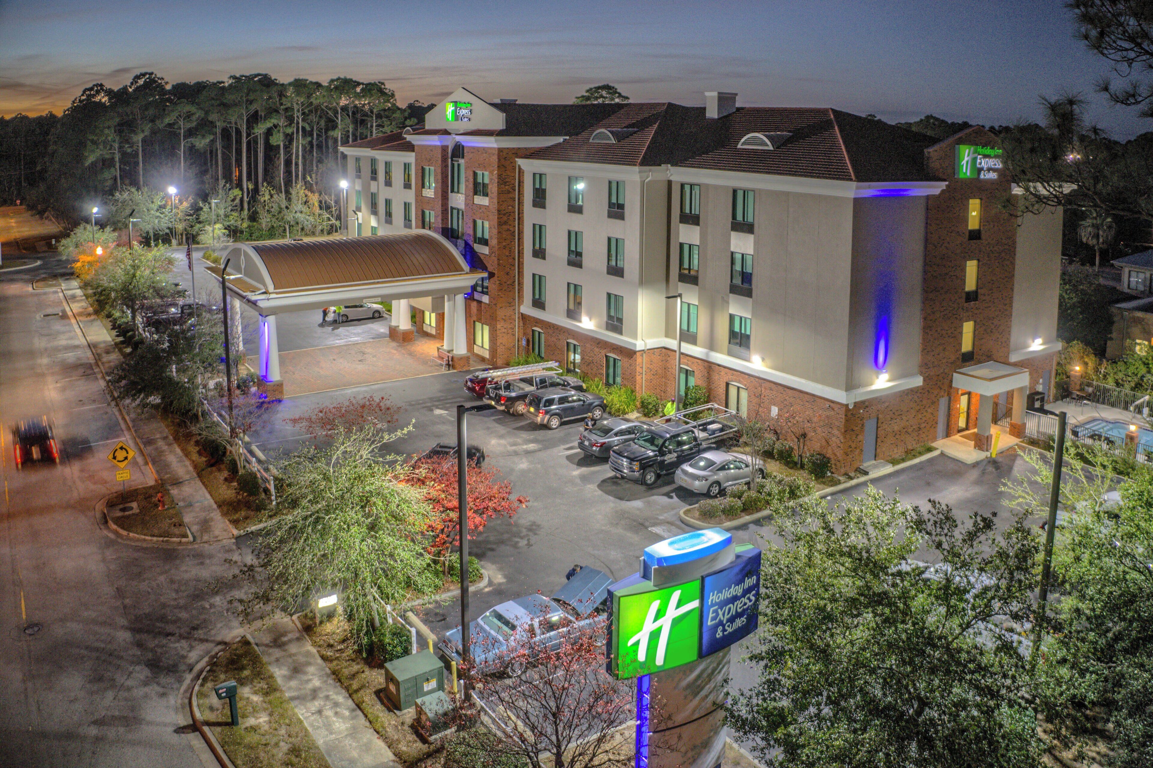 Um hotel Holiday Inn Express com estacionamento, passarela coberta e piscina.