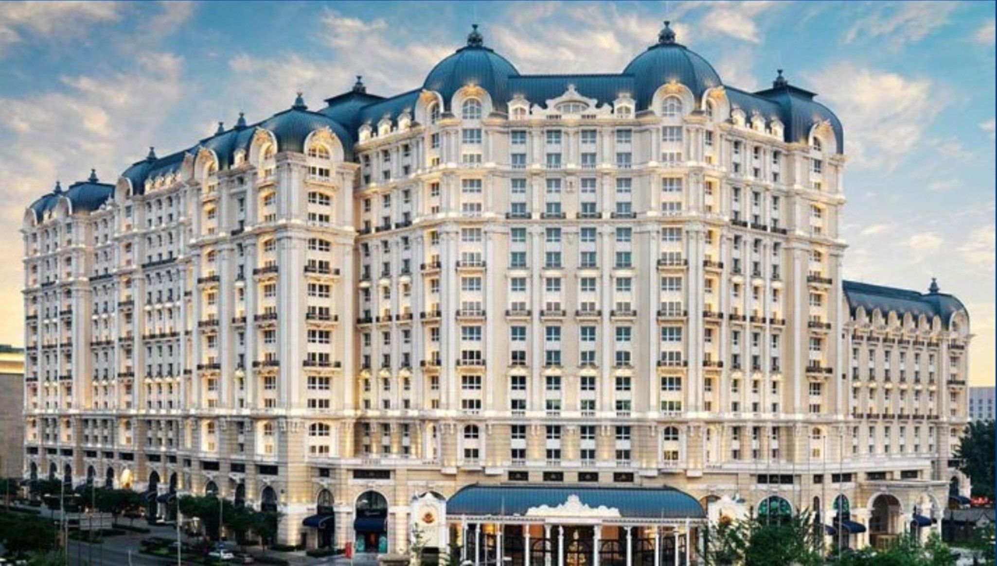 Um hotel grande, com vários andares, de estilo arquitetônico clássico, com várias janelas e uma entrada central com cúpula.