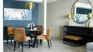 Uma área de jantar moderna com uma mesa redonda, cadeiras de veludo, um balde de champanhe e um espelho grande.