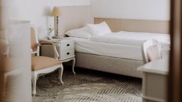 Quarto de hotel com cama, cadeira, mesa de cabeceira e luminária.