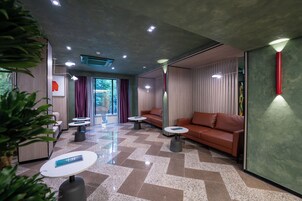 Um lobby moderno com piso xadrez, sofás de couro e mesas redondas.