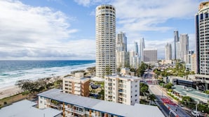 Paisagem costeira com edifícios altos, uma praia e céu claro.